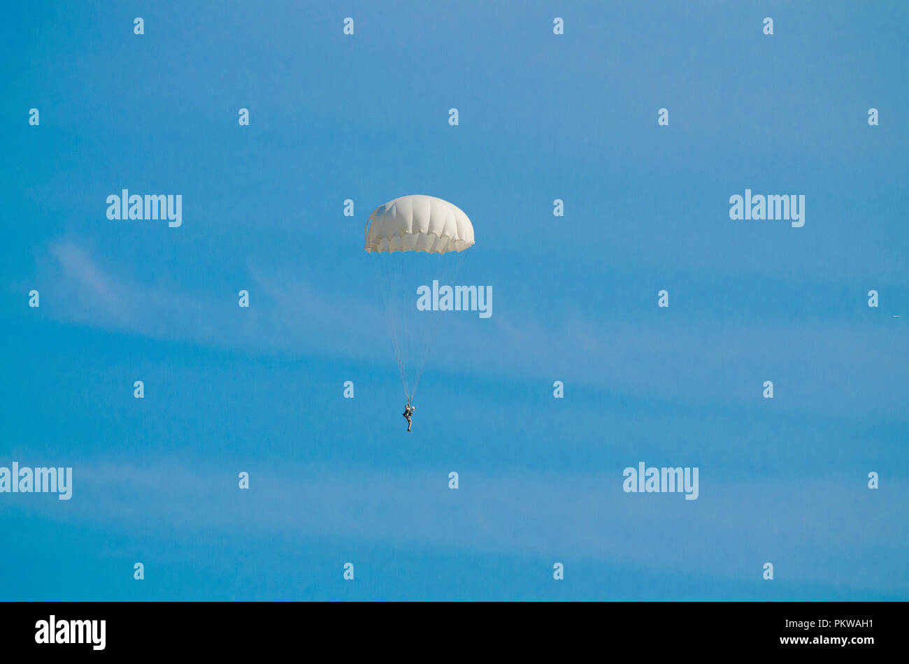 The parachutist. flying in a blue sky on a white dome parachute Stock ...