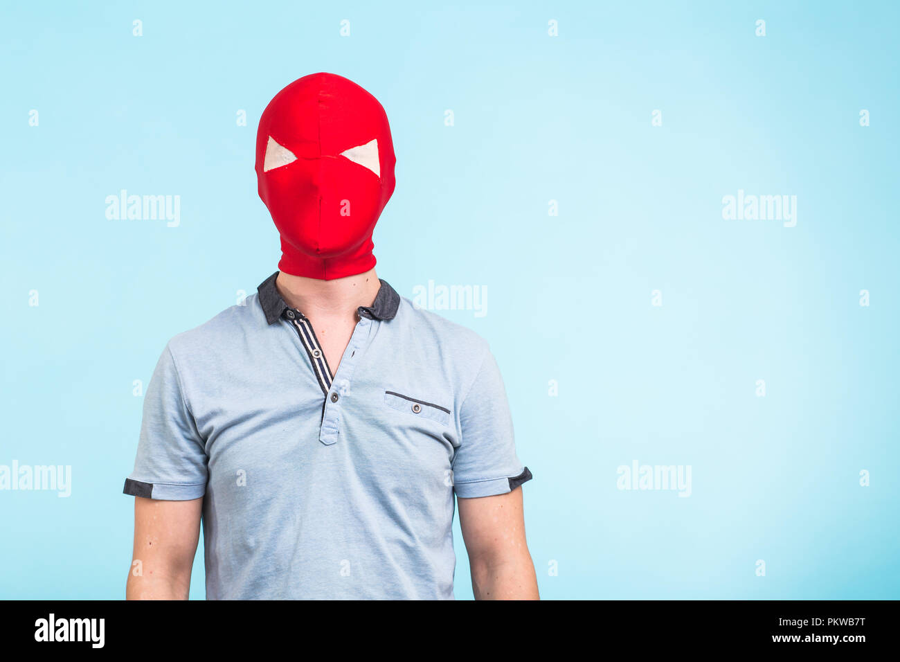 Man wearing red mask on blue background with copy space. Anonymous ...