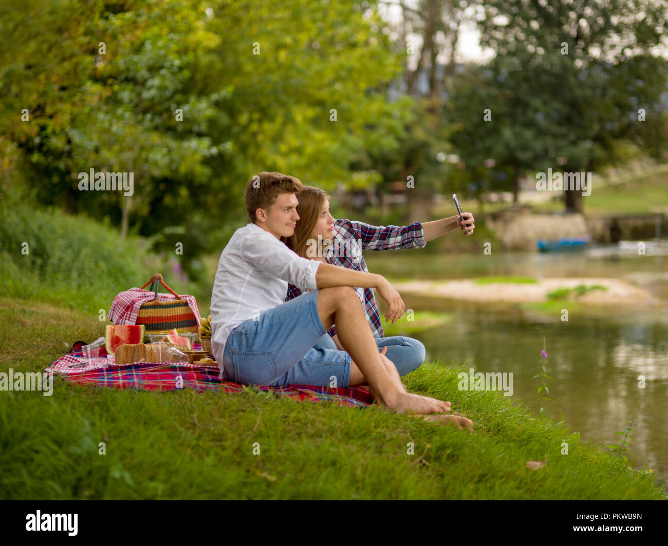 Couple in love taking a selfie by mobile phone while enjoying picnic ...