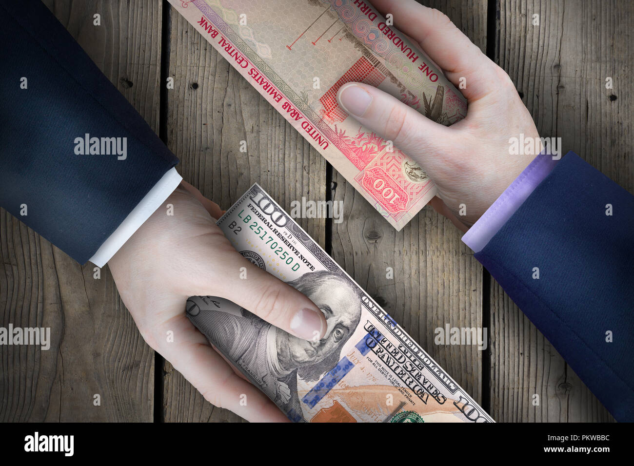Two fiat currency bills being exchanged by two business people as part ...