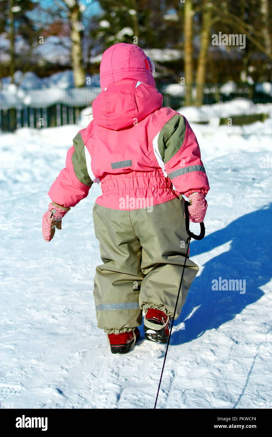 Little girl in overall Pulling sledges in winter Stock Photo - Alamy