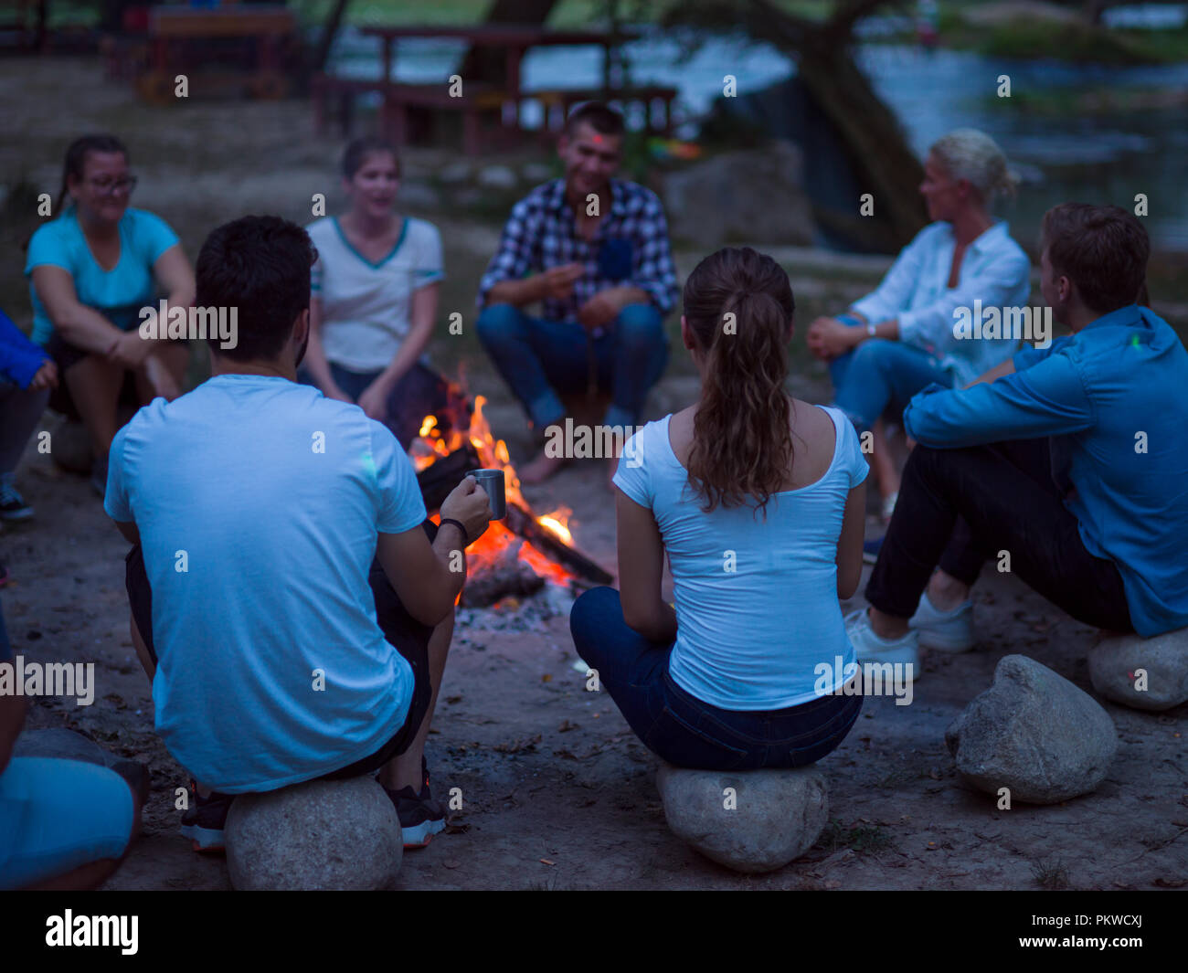a group of happy young friends relaxing and enjoying summer evening ...