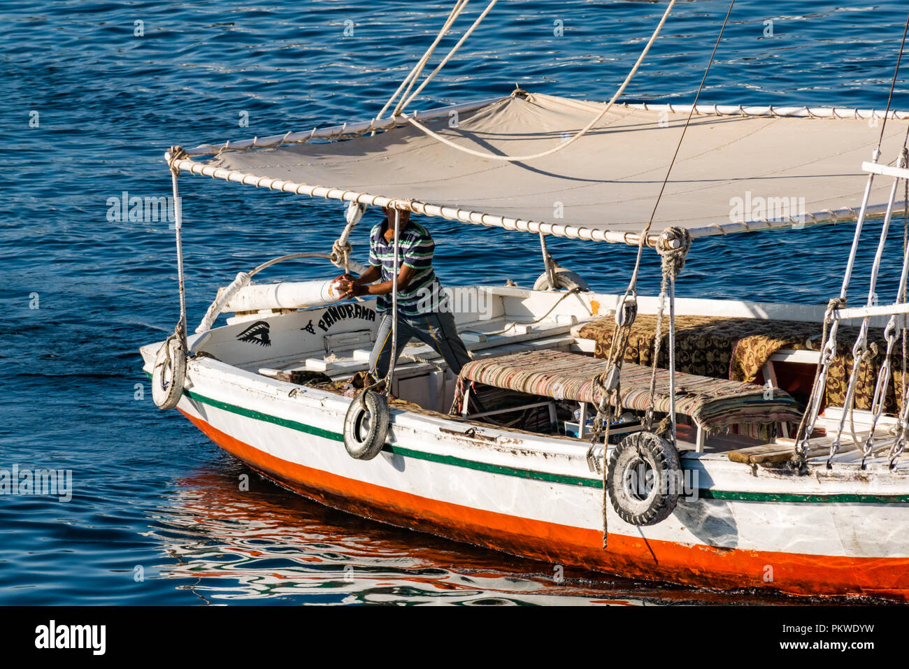 Local Egyptian man under awning at rudder of traditional felucca ...