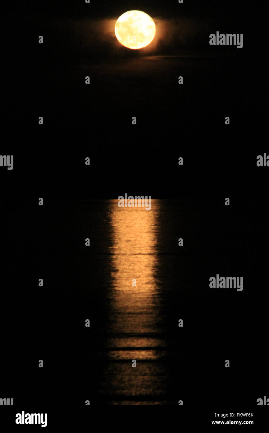 Full moon rising over the ocean Stock Photo - Alamy