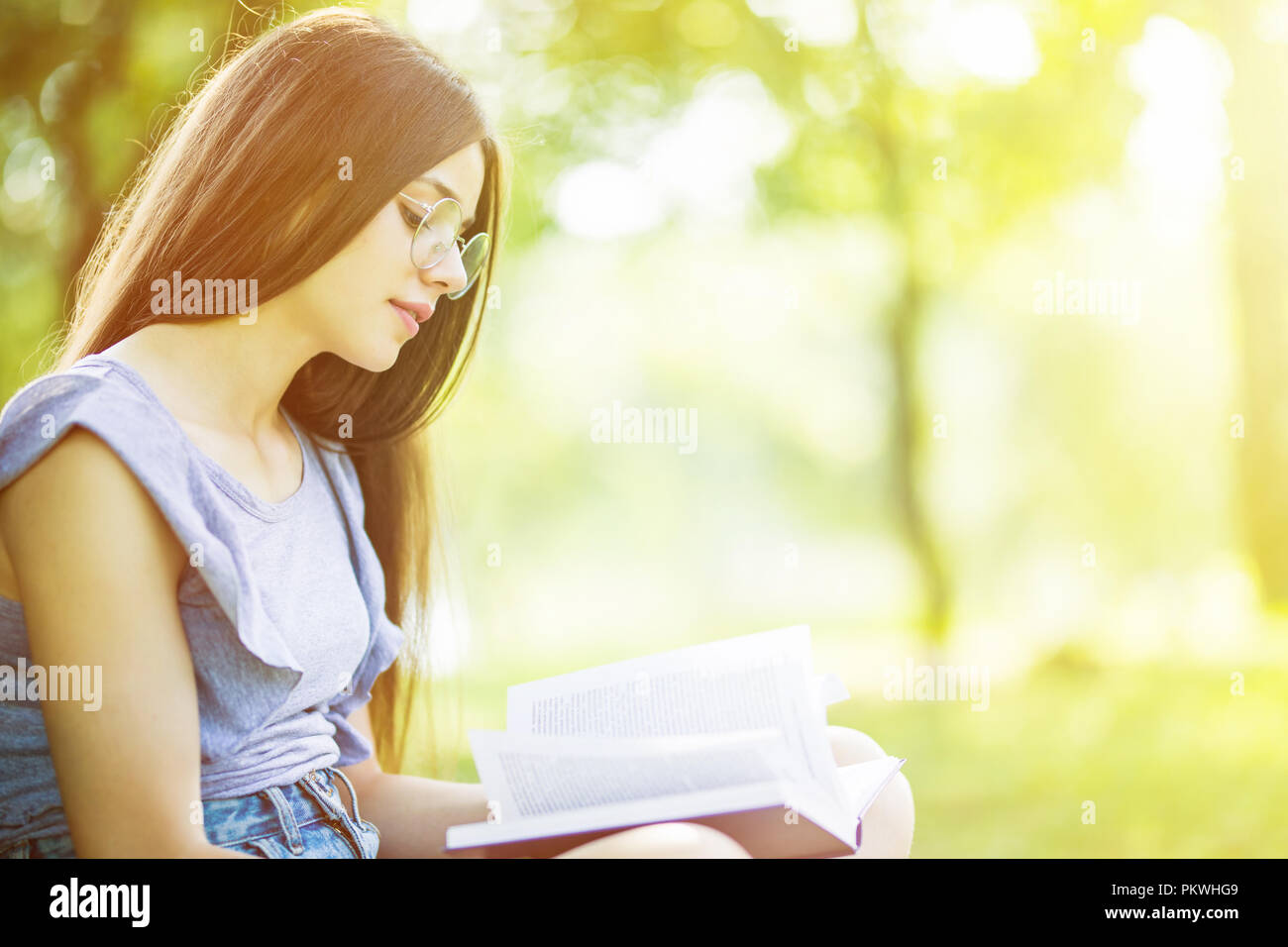 girl reading book at park in summer sunset light Stock Photo - Alamy
