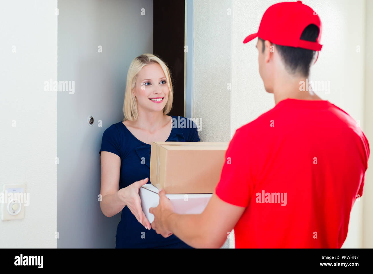 Happy woman getting her order from delivery man Stock Photo - Alamy
