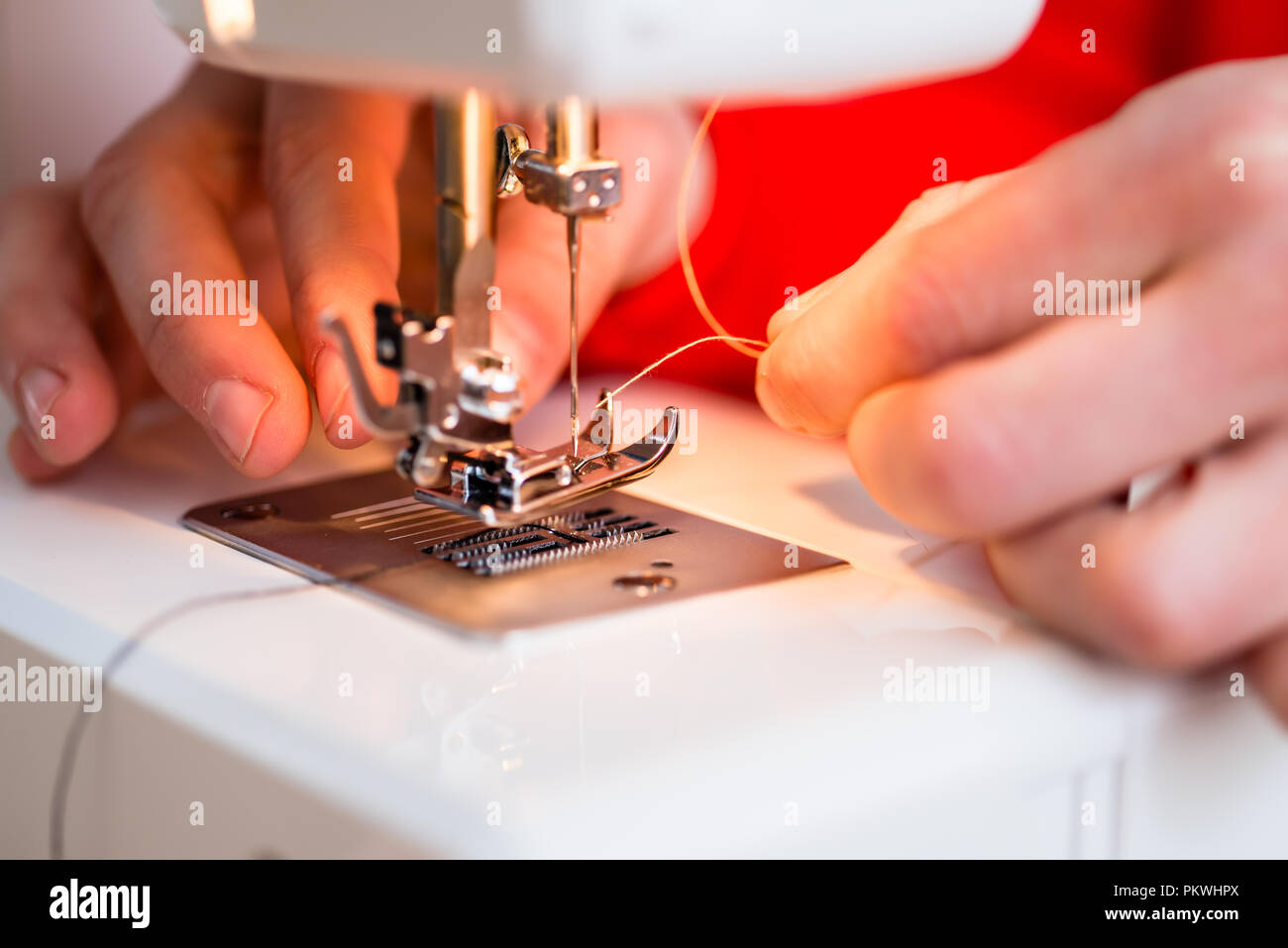 Person inserting thread in to a needle Stock Photo - Alamy