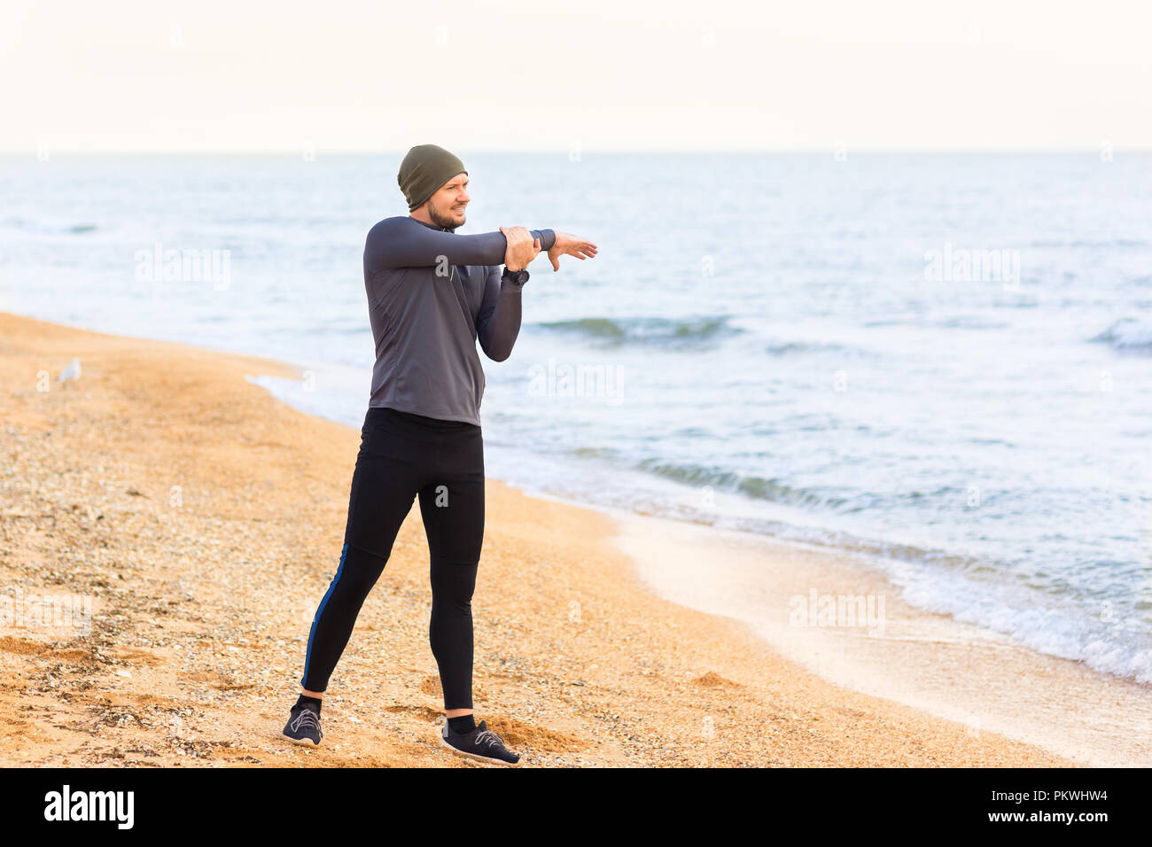 man doing stretch exercises on the sea beach Stock Photo - Alamy
