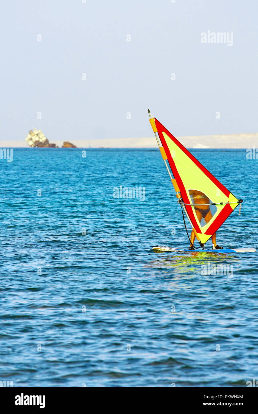 Windsurfer, blue sea and yellow sail. Surfer exercising in calm sea or ...