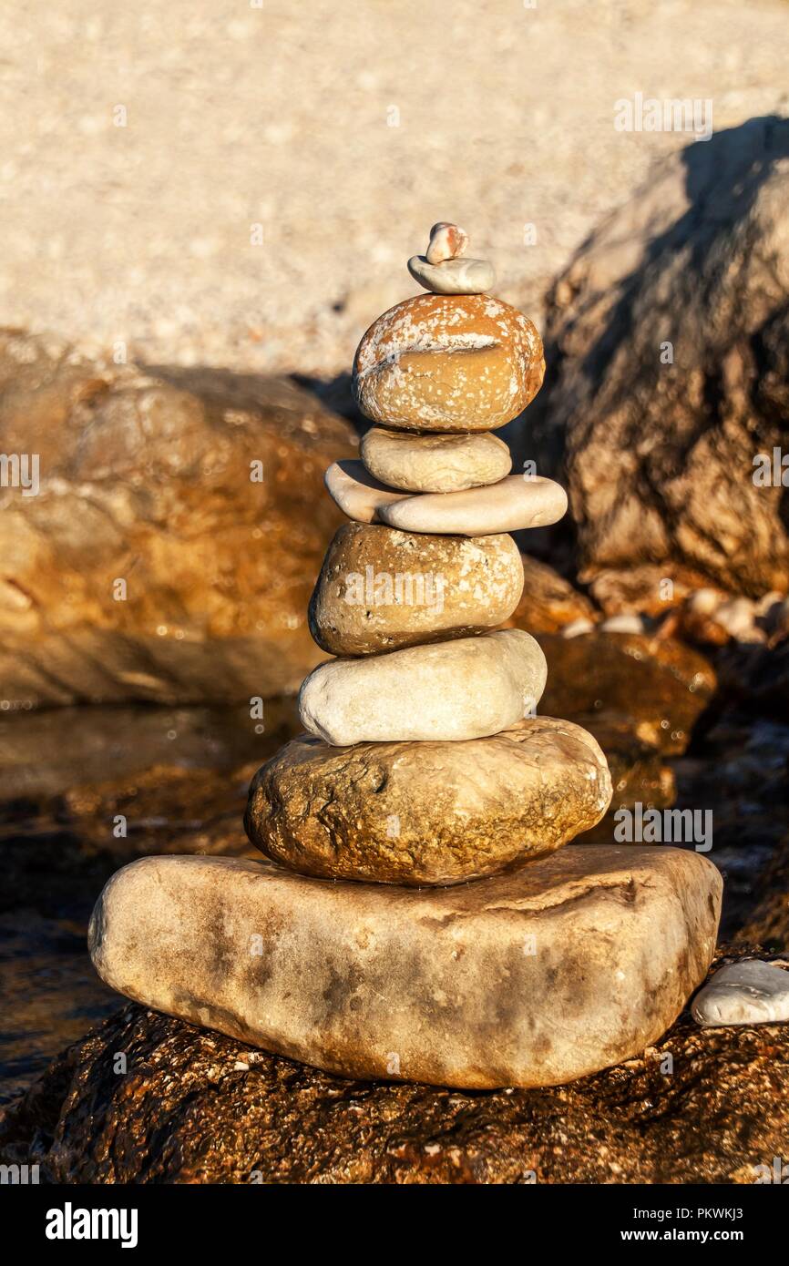 Pebble stack on the seashore. Pyramid of stones on the beach. Light at ...