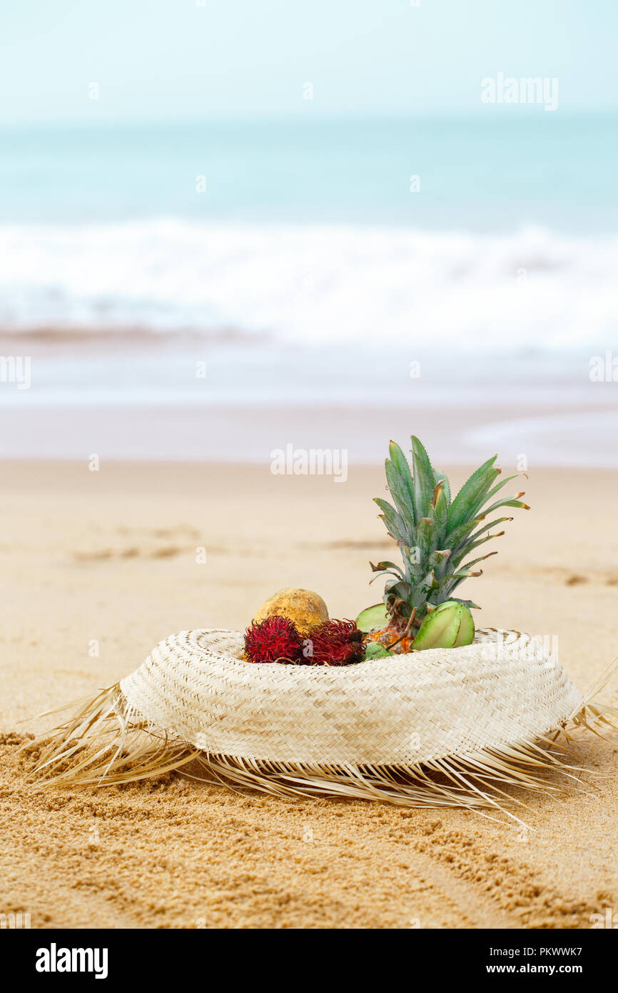 Exotic fruits in a straw hat near the ocean Stock Photo - Alamy
