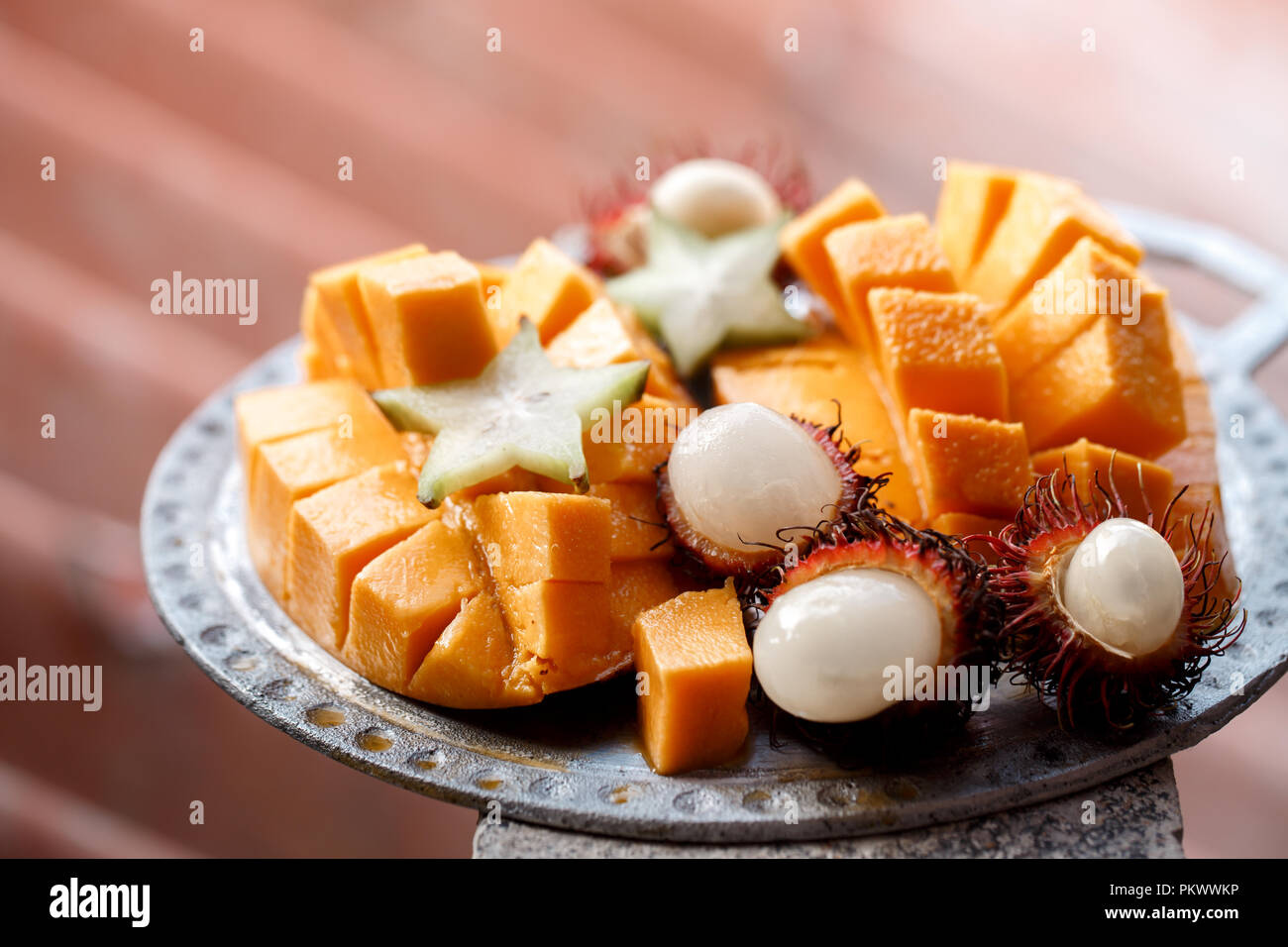 Juicy, ripe mango, rambutan and Cannon on a metal plate Stock Photo - Alamy
