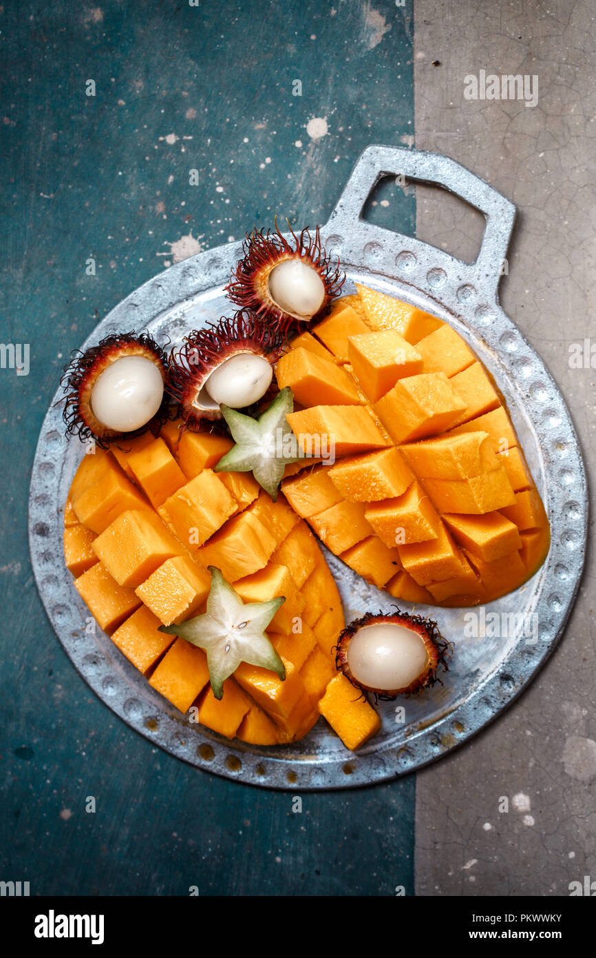 Juicy, ripe mango, rambutan and Cannon on a metal plate Stock Photo - Alamy