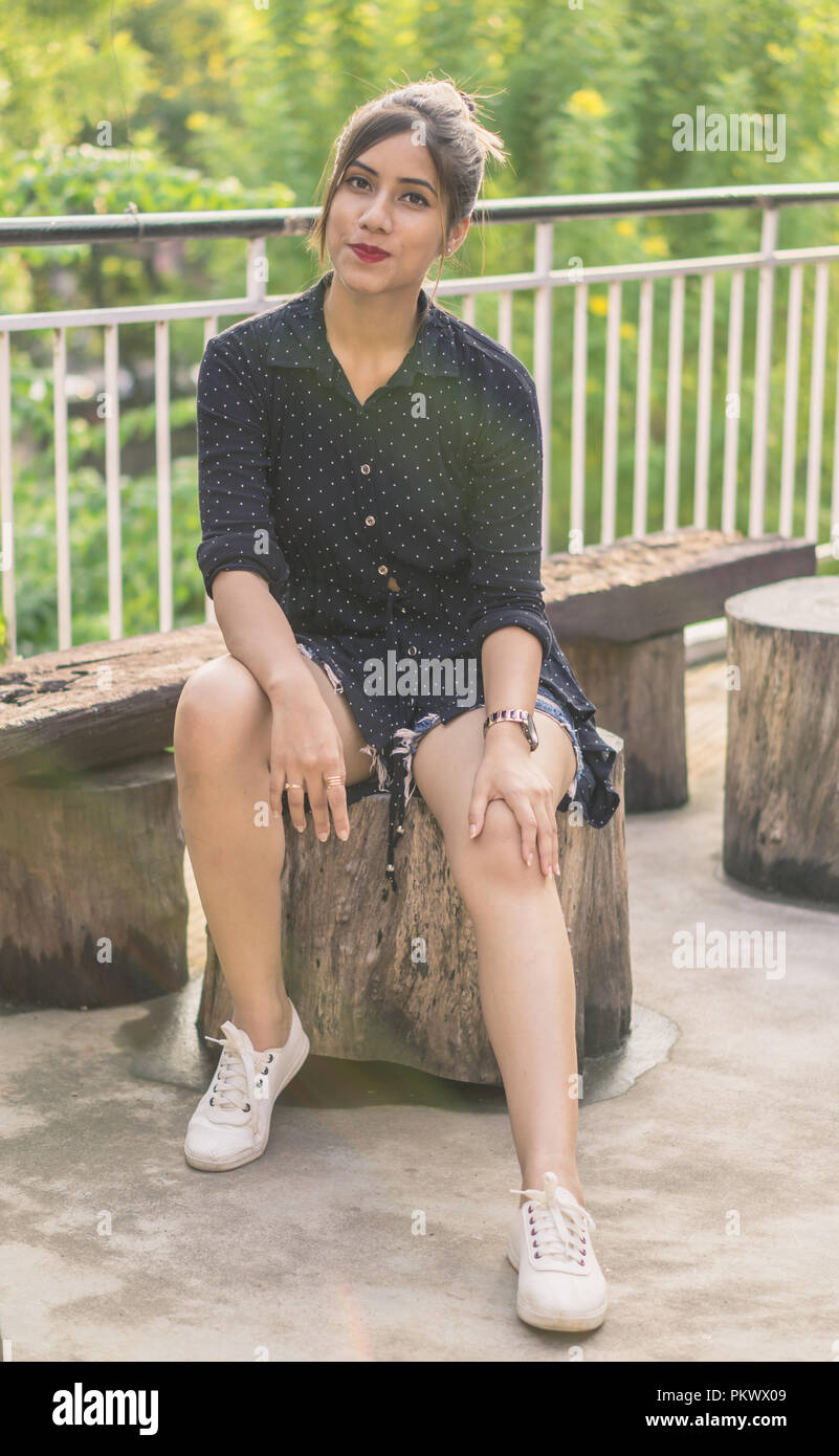 Girl posing for the camera while sitting on a wooden platform in a ...