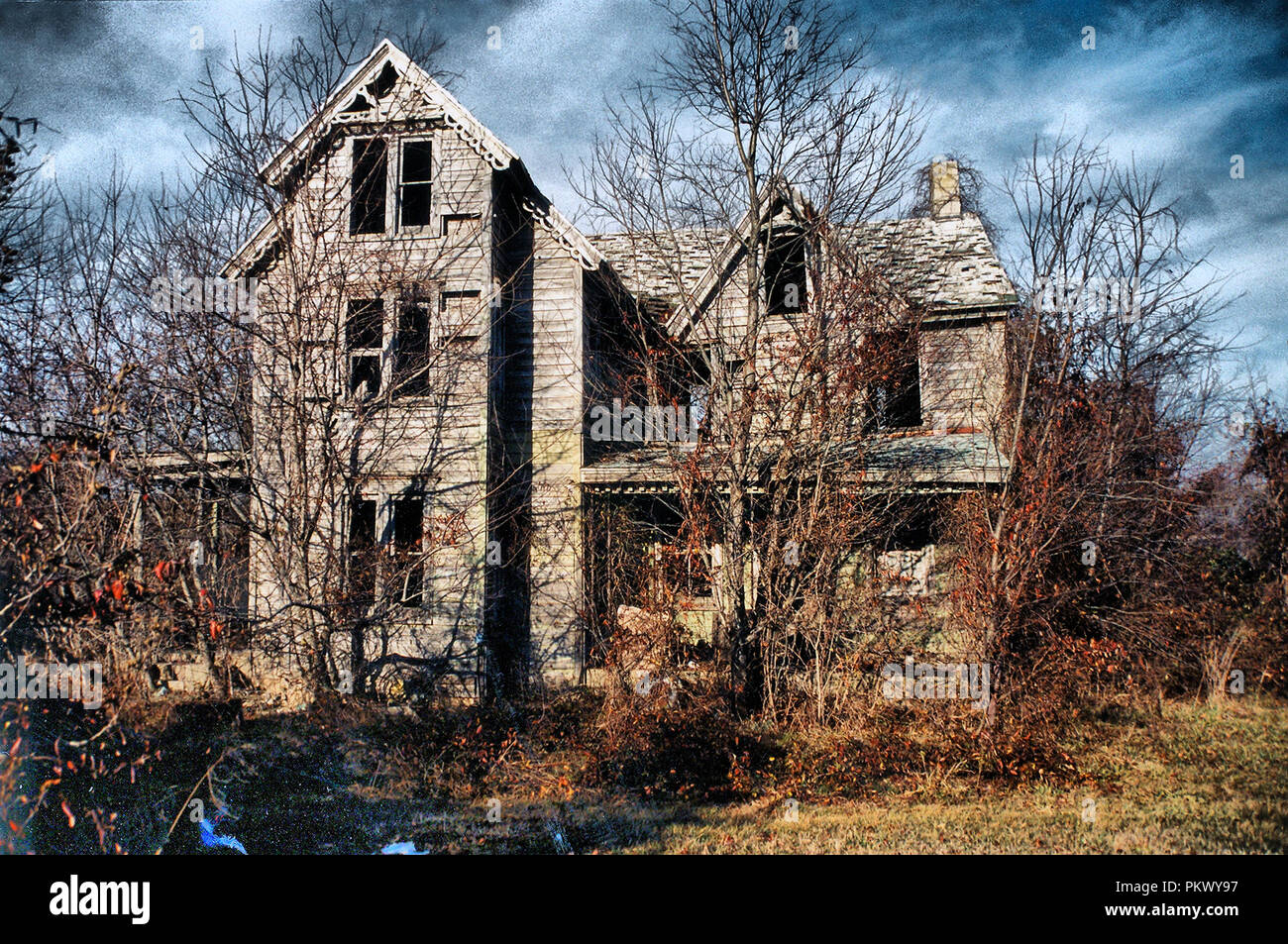Old broken down and weathered three-story home with broken windows ...