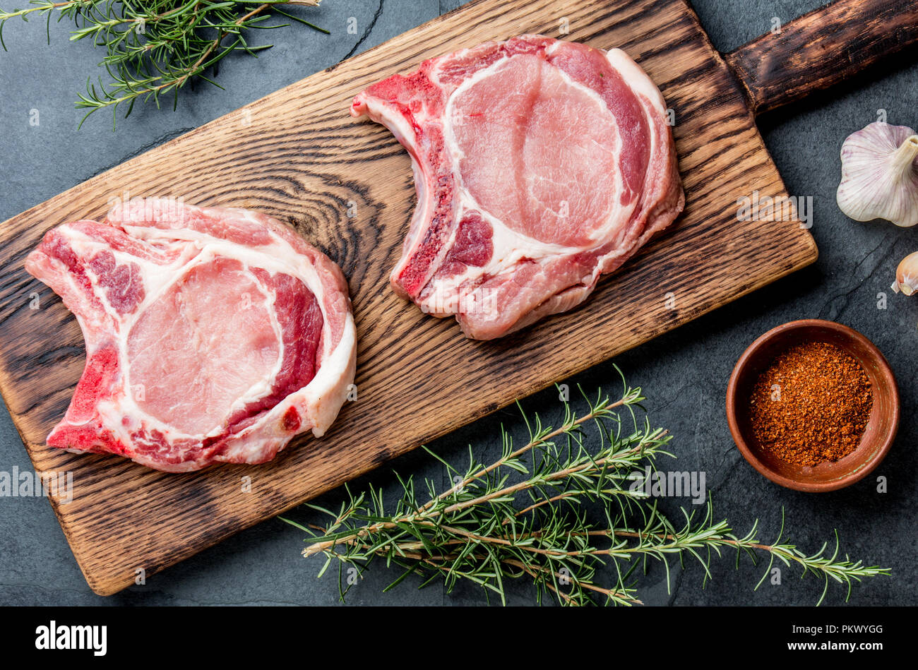 Raw pork steaks with seasoning on wooden board. Gray slate background ...