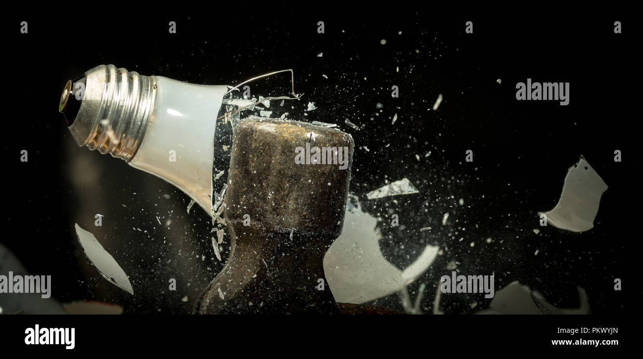 Light bulb breaks into glass shards as it hits a hammer Stock Photo - Alamy