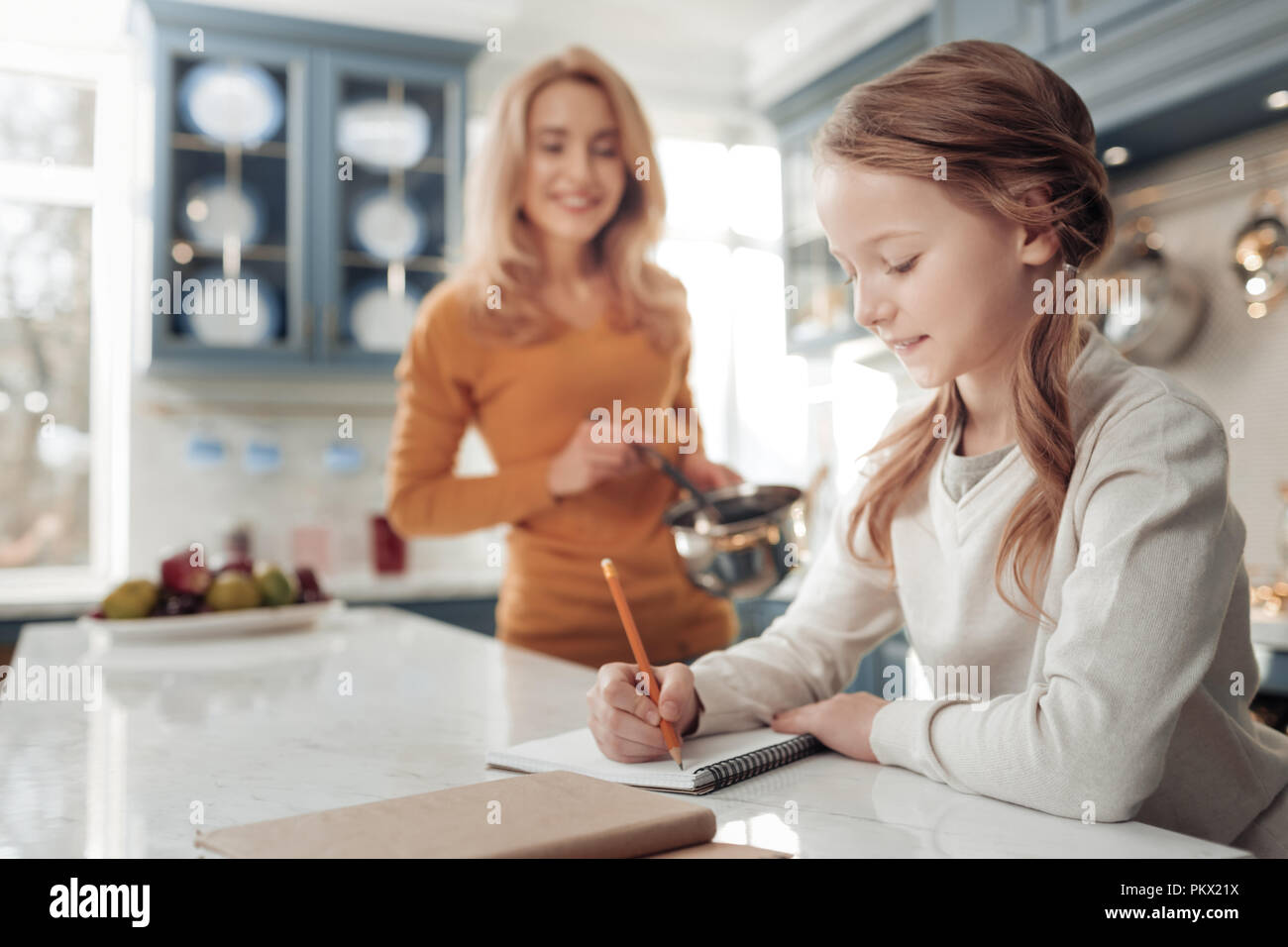 Attentive little girl making notes in copybook Stock Photo - Alamy