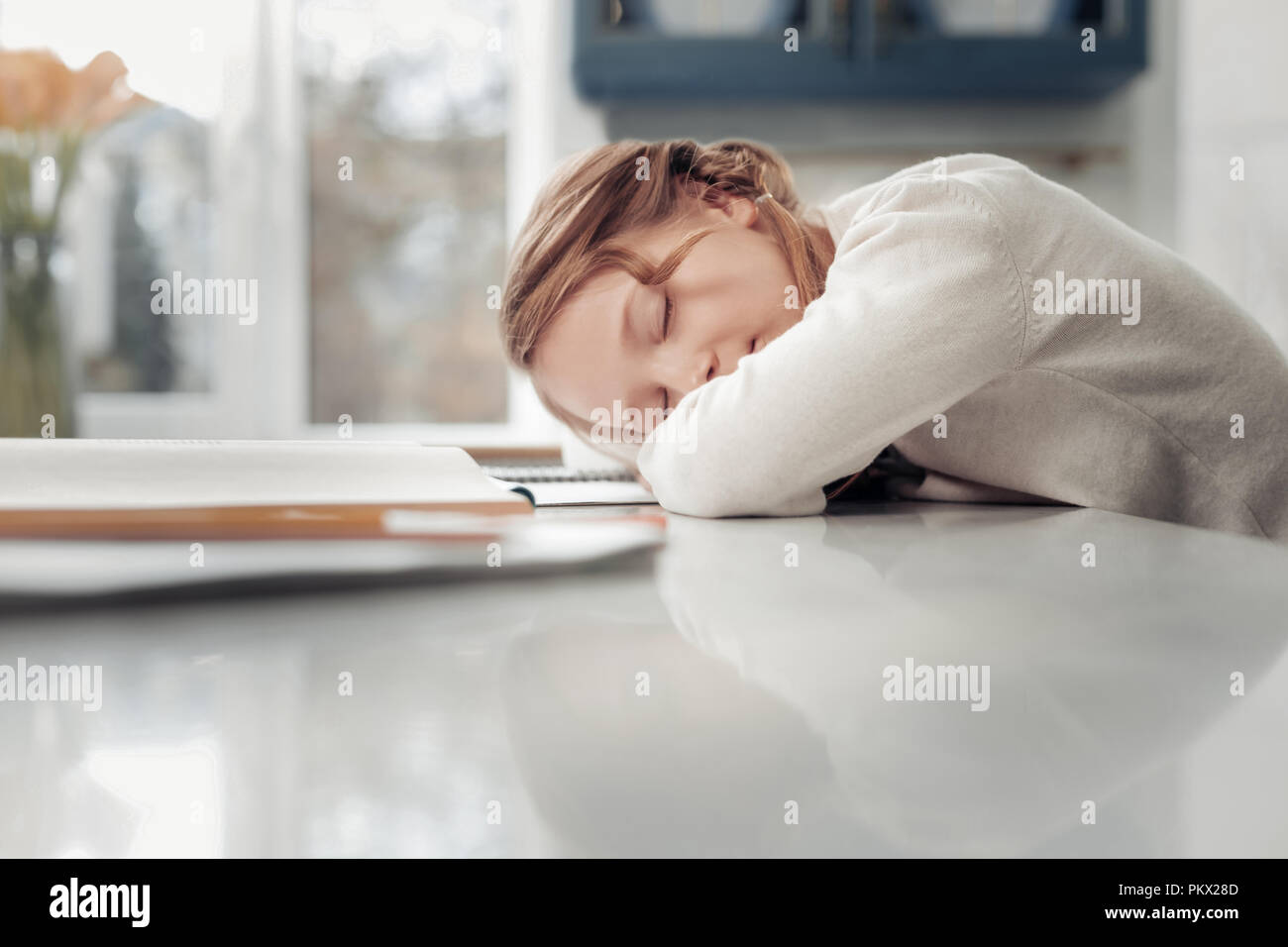 Exhausted little girl lying on table at home Stock Photo - Alamy