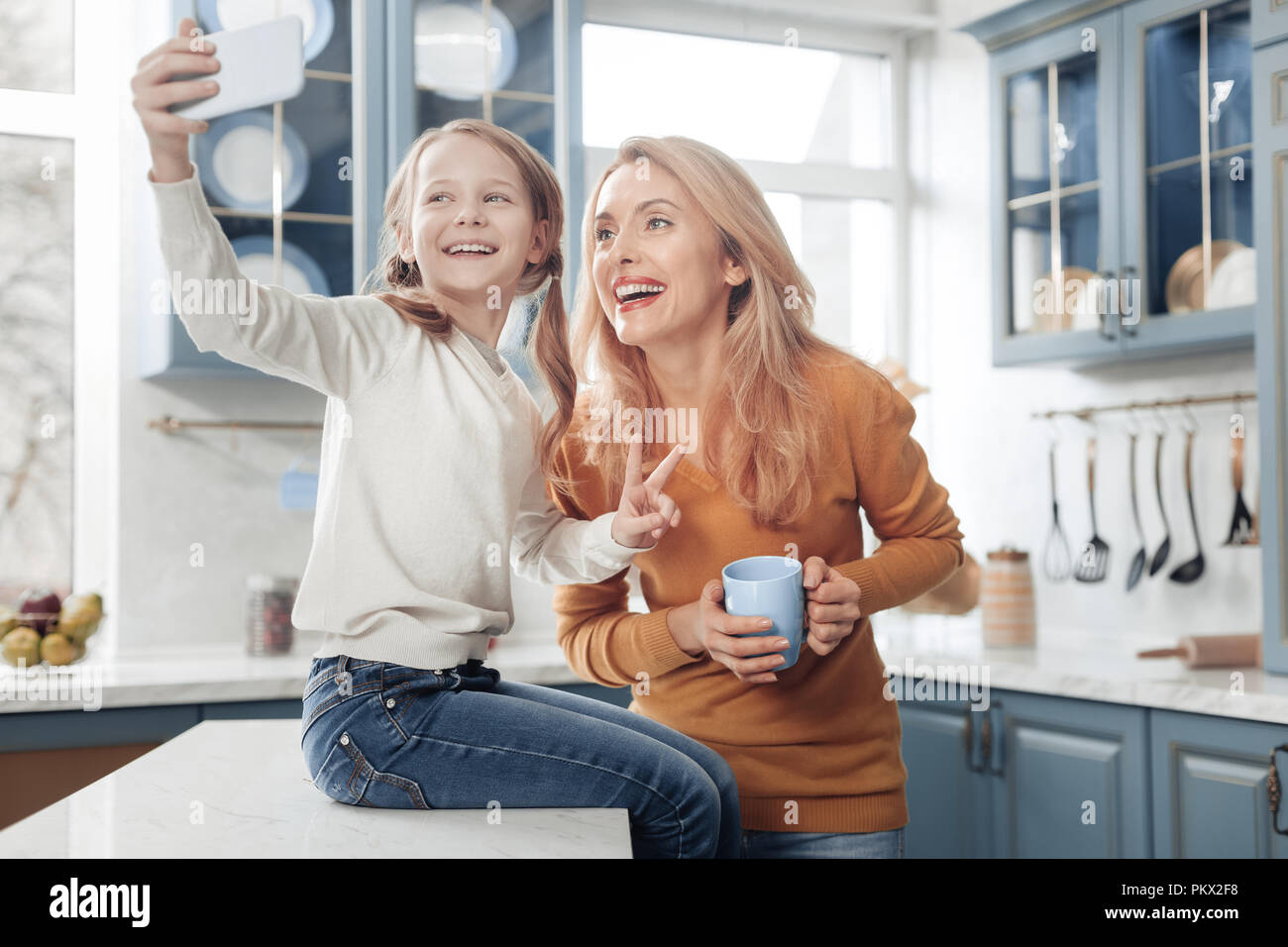 Joyful little girl taking picture with mom Stock Photo - Alamy