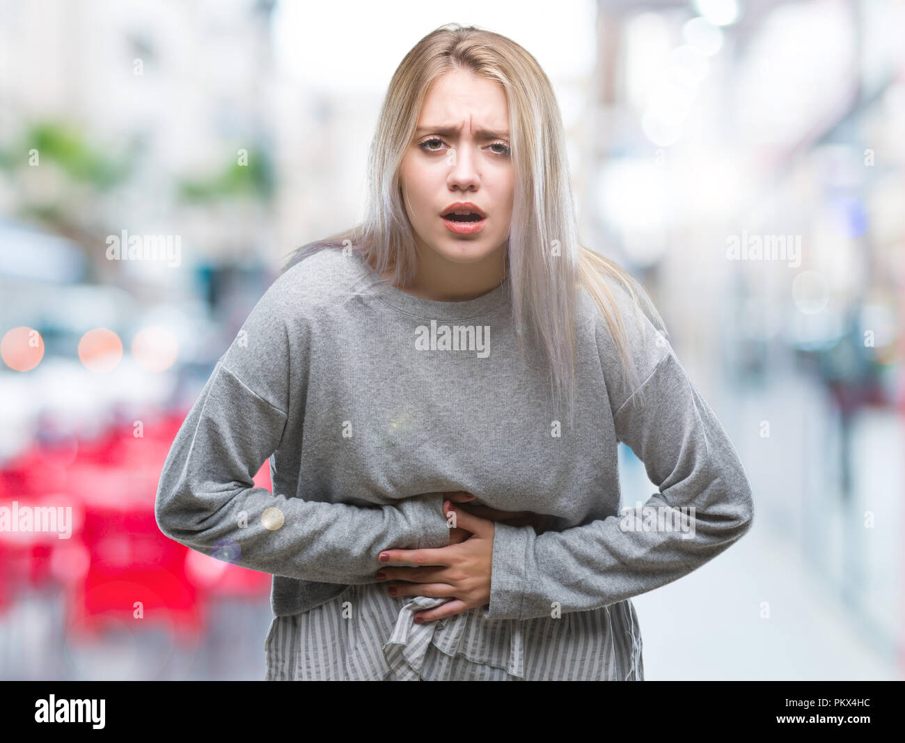Young blonde woman over isolated background with hand on stomach ...