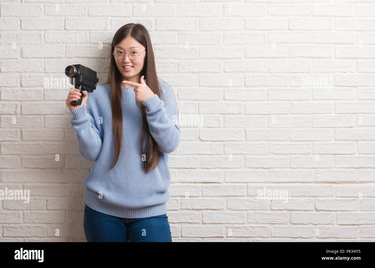 Young Chinese woman filming holding video camera very happy pointing ...