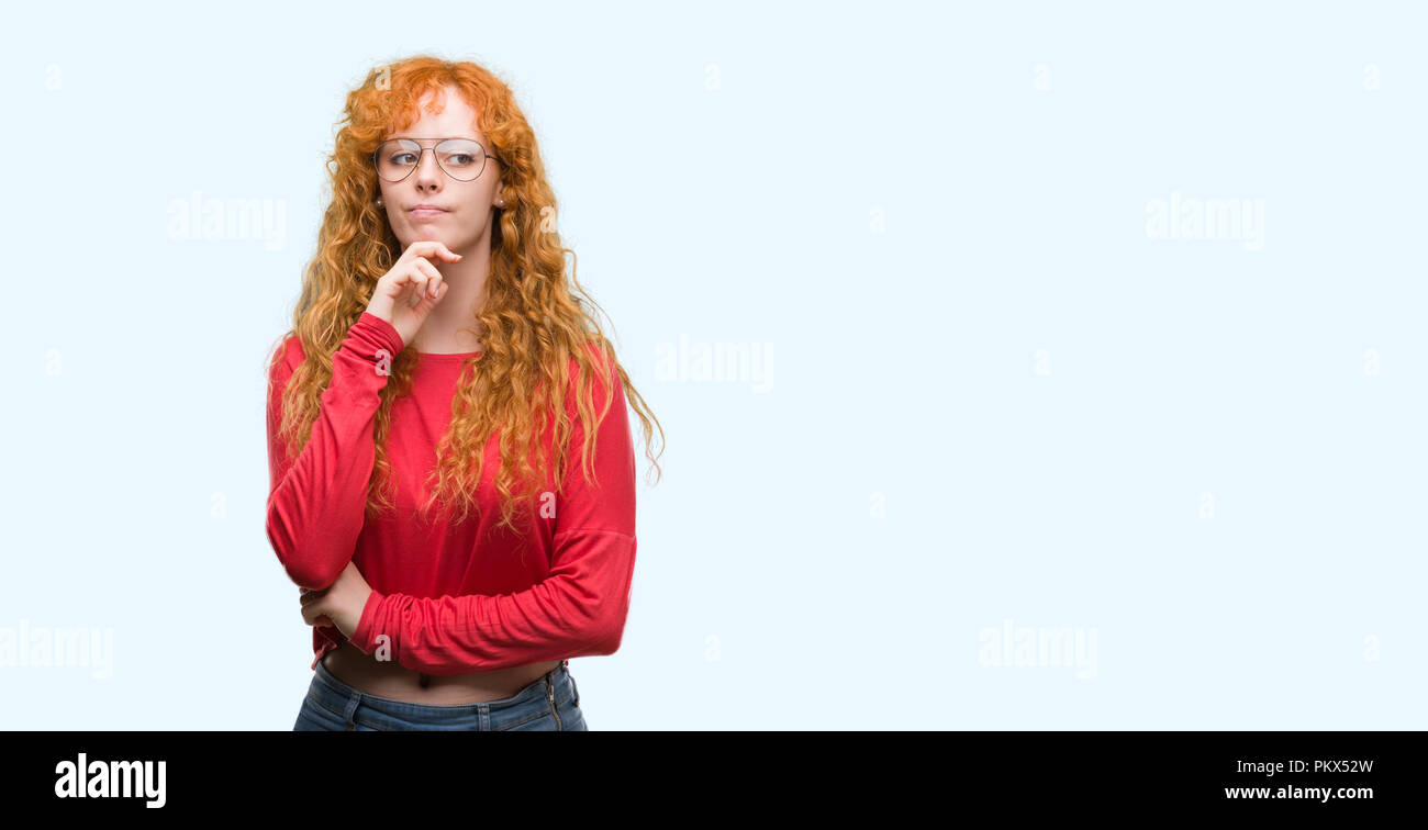 Young redhead woman wearing glasses serious face thinking about ...