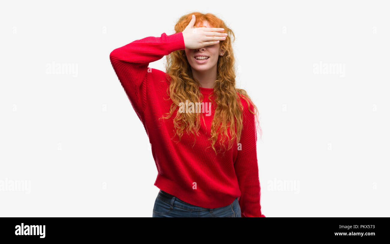 Young redhead woman wearing red sweater smiling and laughing with hand ...