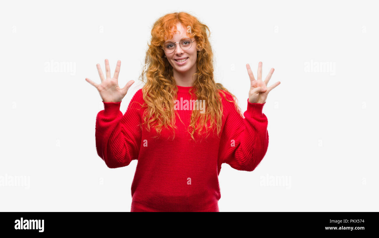 Young redhead woman wearing red sweater showing and pointing up with ...