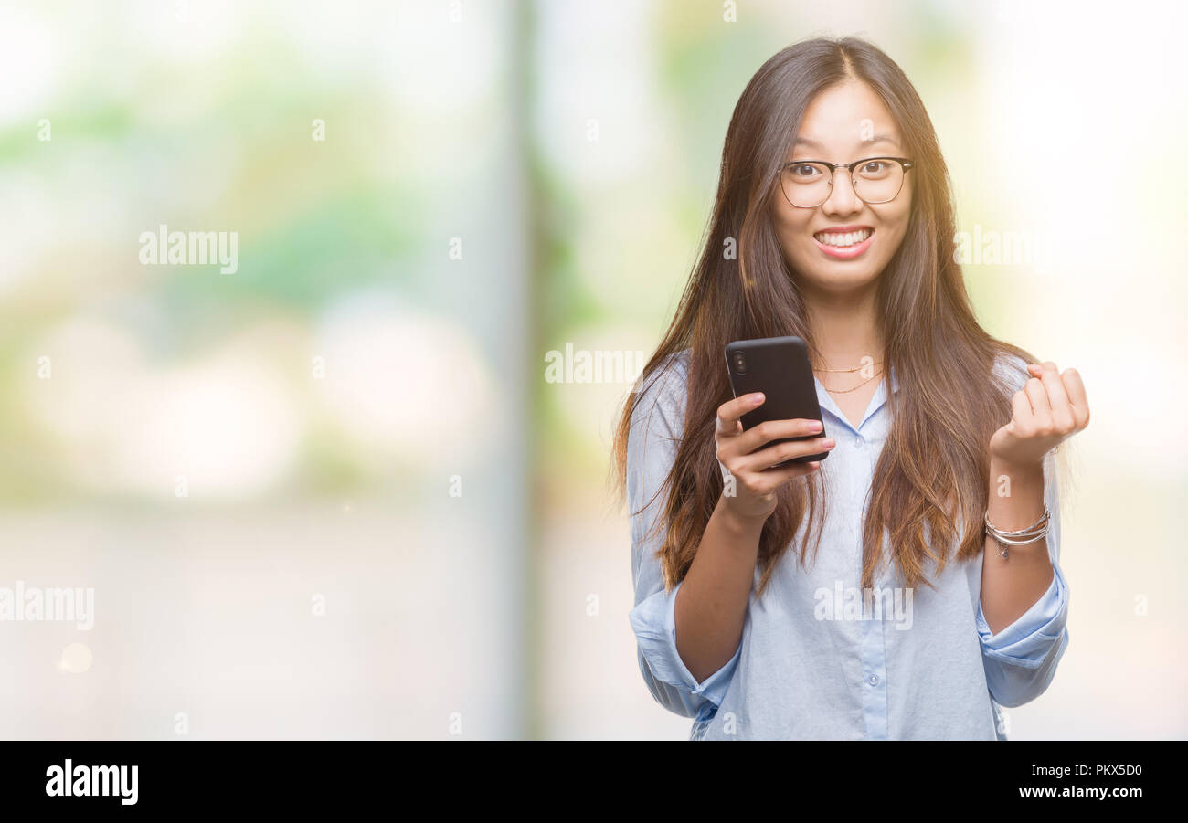 Young asian woman texting using smartphone over isolated background ...