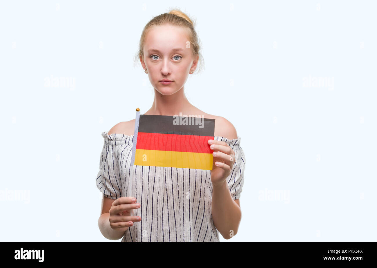 Blonde teenager woman holding flag of Germany with a confident ...