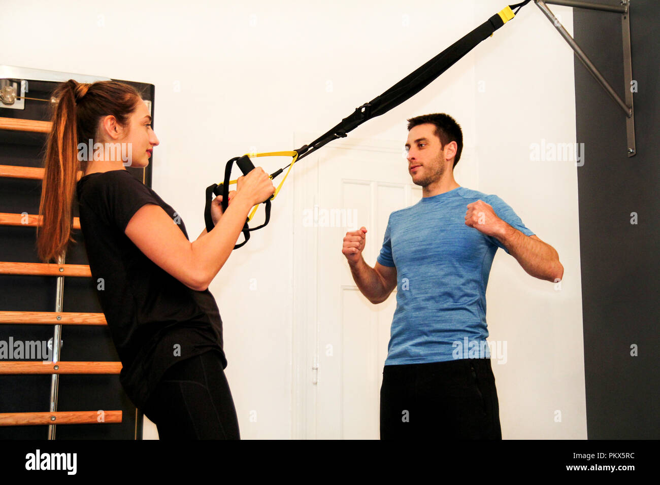 Beautiful pretty fitness sporty woman with help of her personal trainer ...