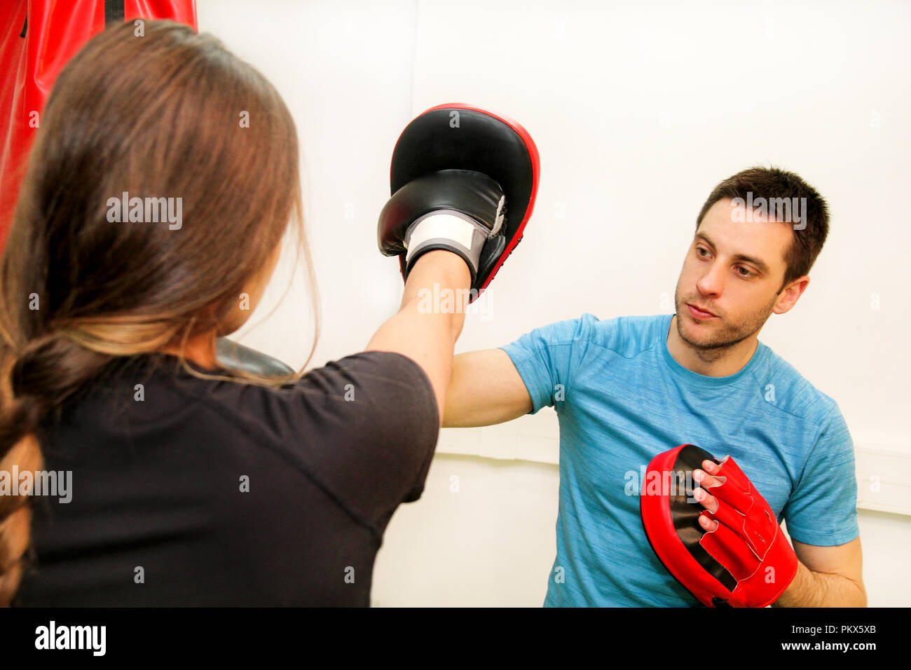 The female boxer training at gym. Young sporty woman punching her male ...