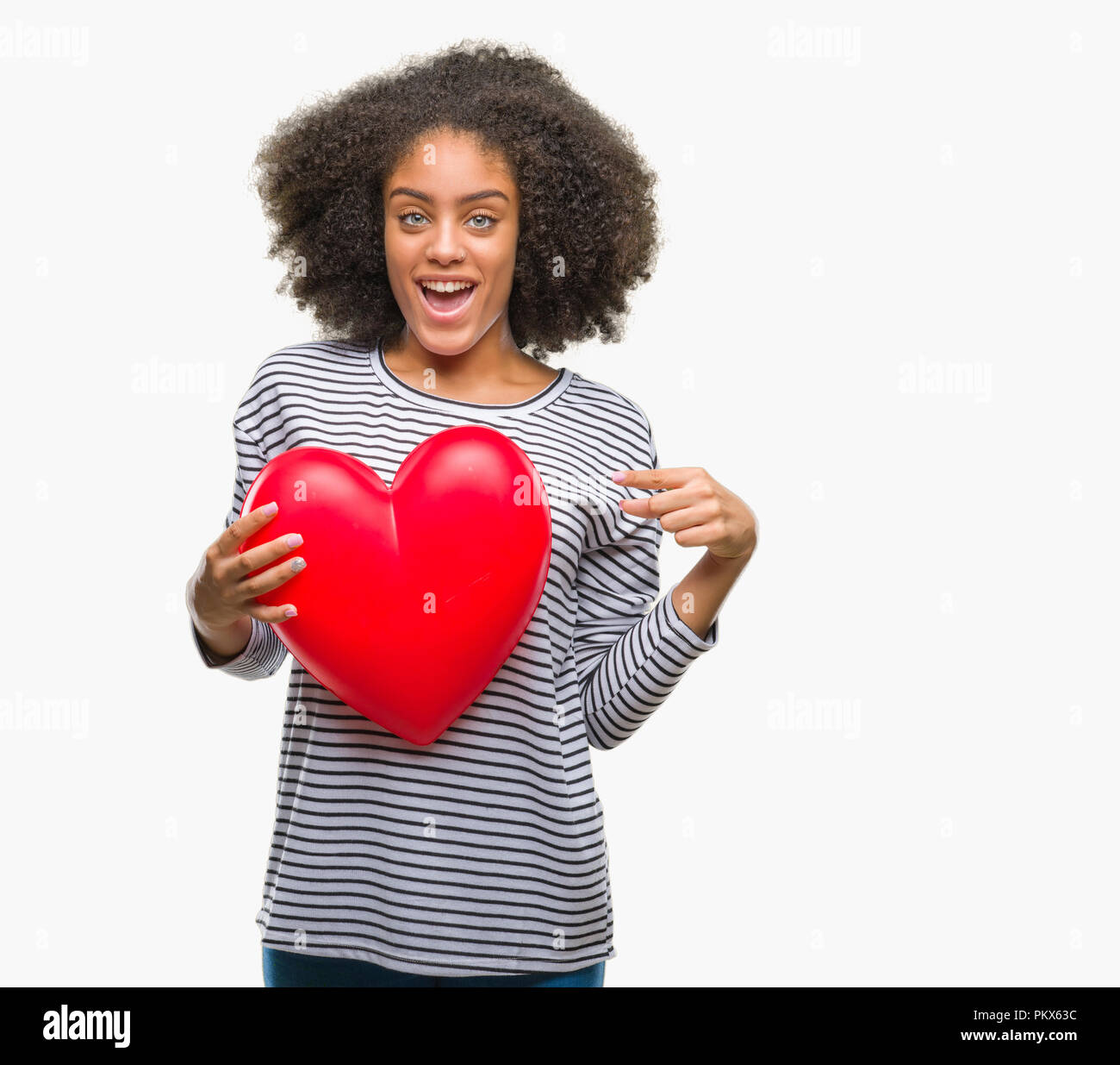 Young afro american woman holding red heart in love over isolated ...