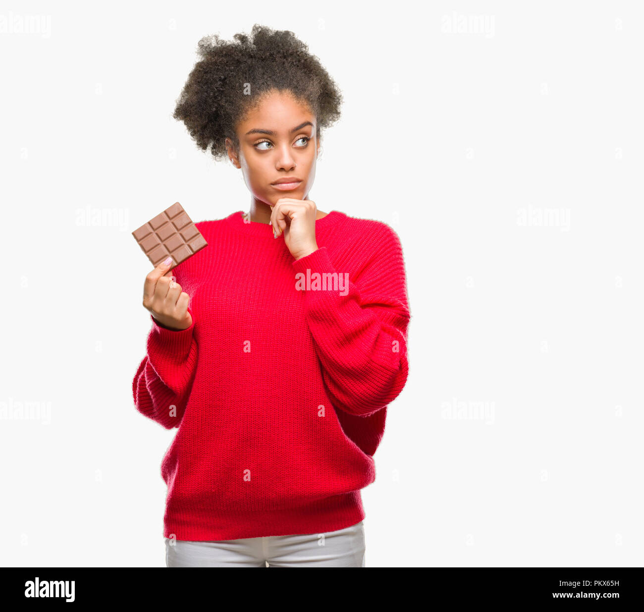 Young afro american woman eating chocolate bar over isolated background ...
