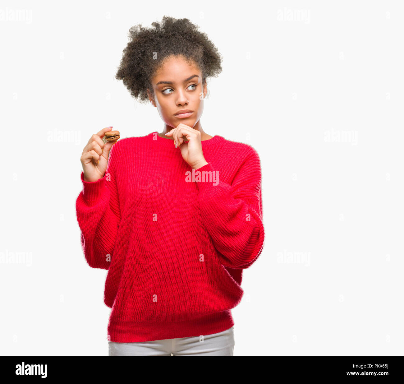 Young afro american woman eating chocolate macaron over isolated ...