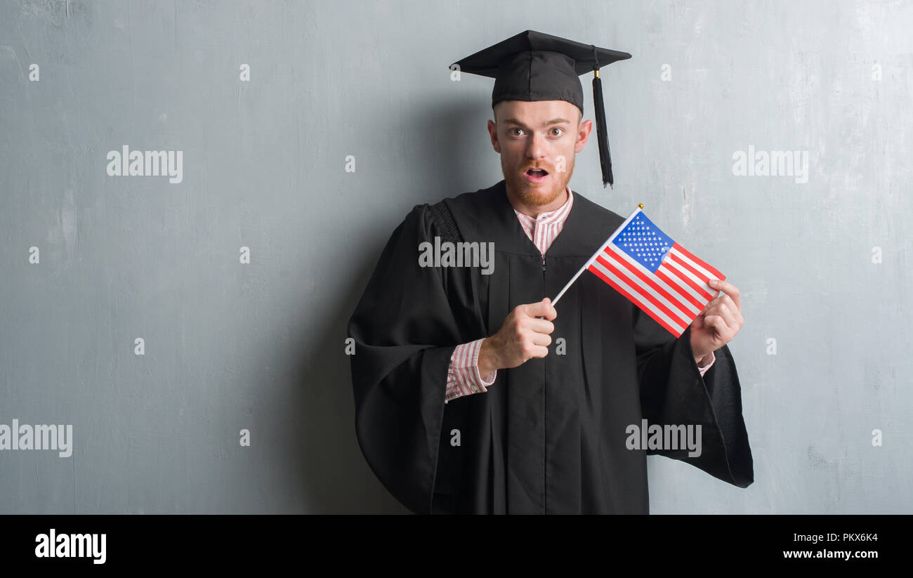 Young redhead man over grey grunge wall wearing graduate uniform ...