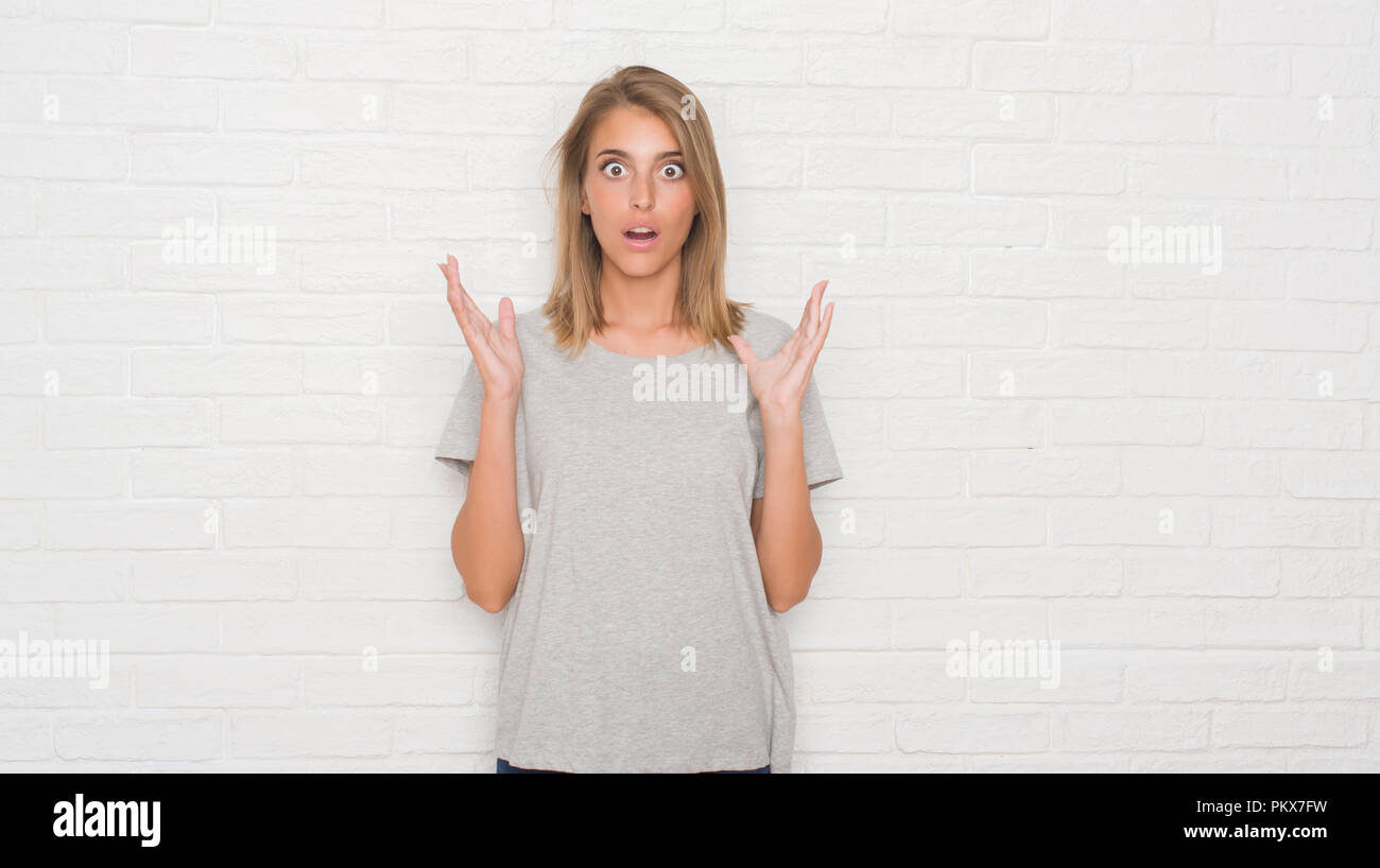Beautiful Young Woman Over White Brick Wall Afraid And Shocked With