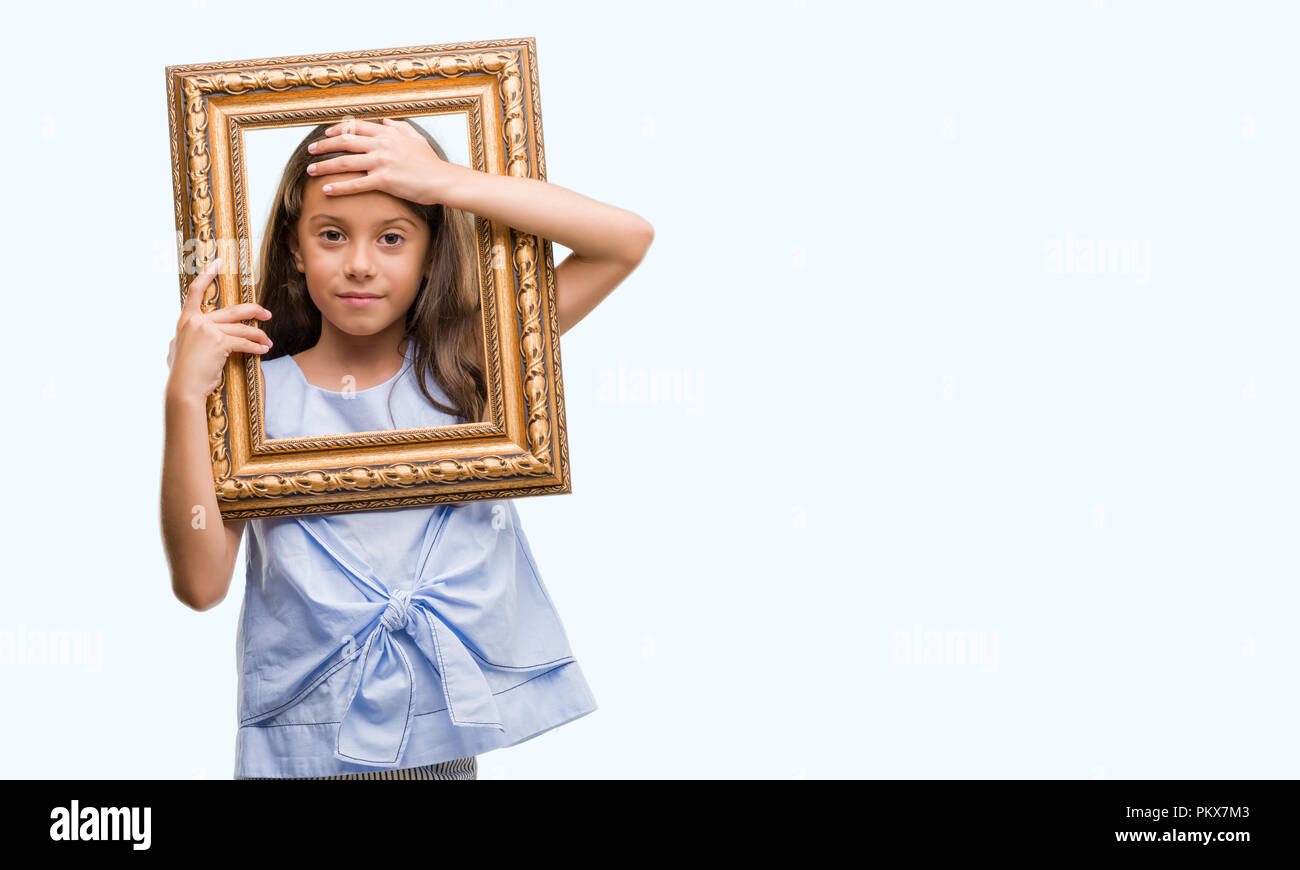 Brunette hispanic girl holding vintage art frame stressed with hand on ...