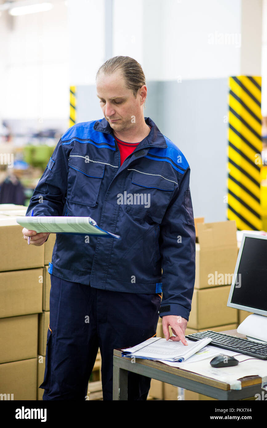 Factory worker doing paperwork in a factory warehouse Stock Photo - Alamy