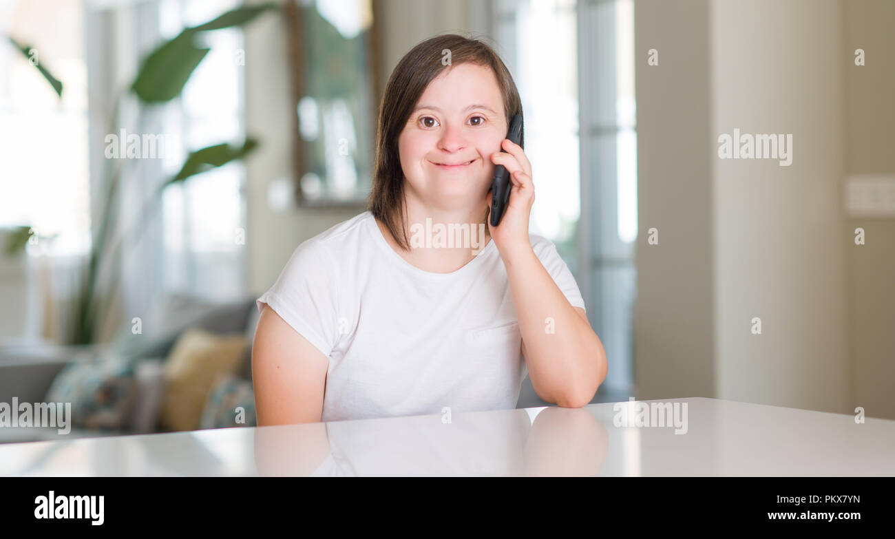 Down syndrome woman at home using smartphone with a happy face standing ...