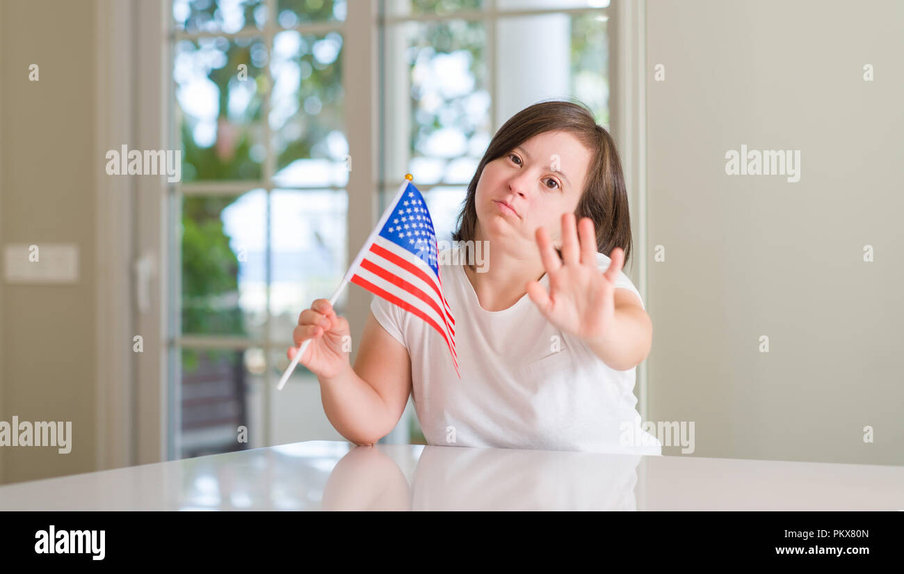 Down syndrome woman at home holding flag of usa with open hand doing ...
