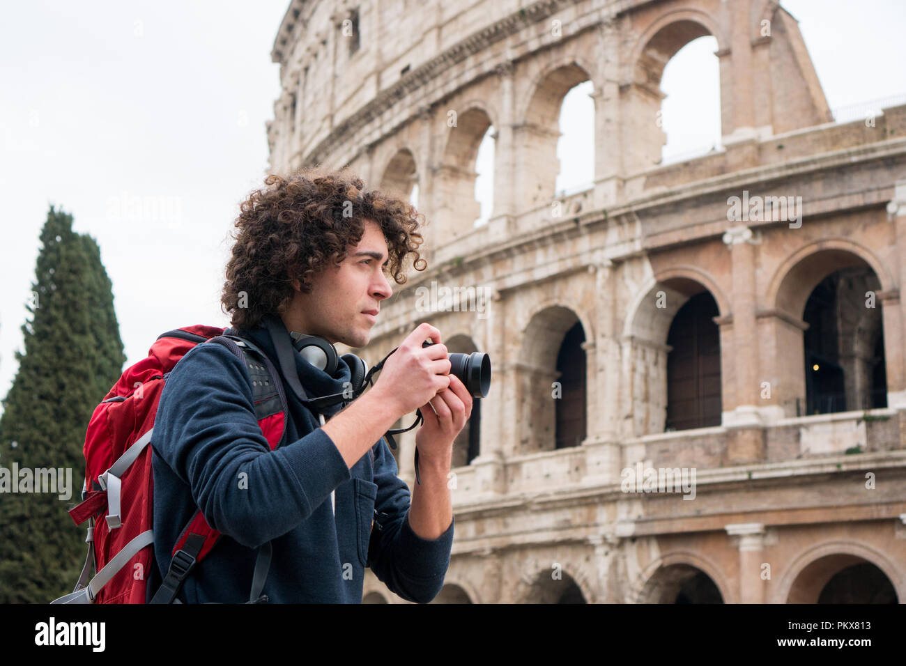 Handsome young tourist man with a camera and backpack taking pictures ...