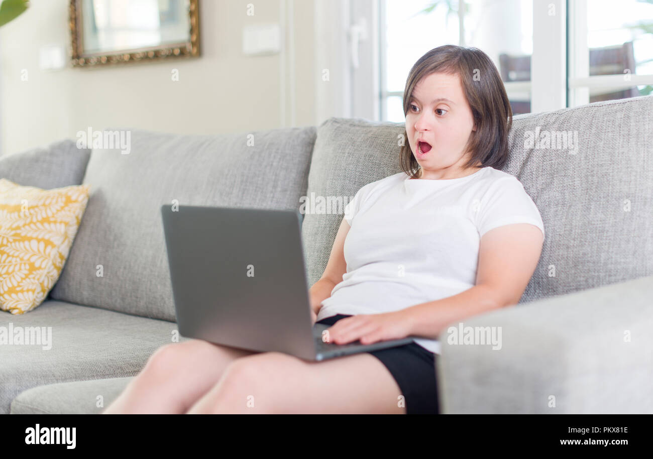 Down syndrome woman at home using computer laptop scared in shock with ...