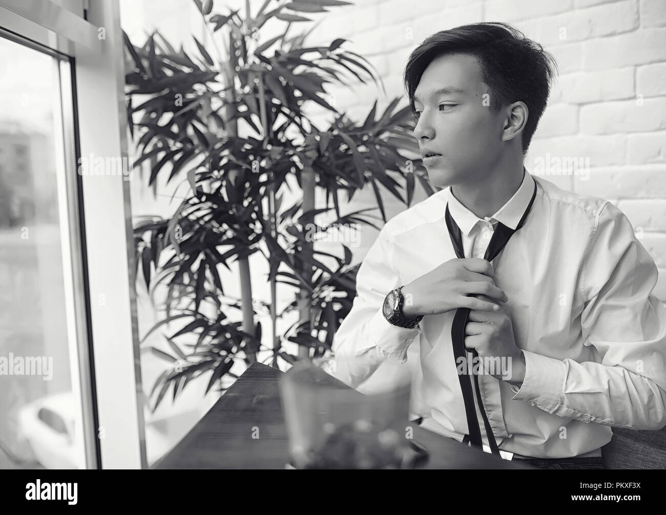 A young Asian businessman is waiting for a partner in a cafe. Bu Stock ...