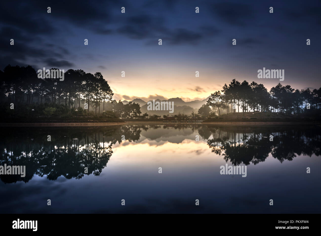 Beautiful dawn on the lake with pink clouds and reflecting sun rays at ...
