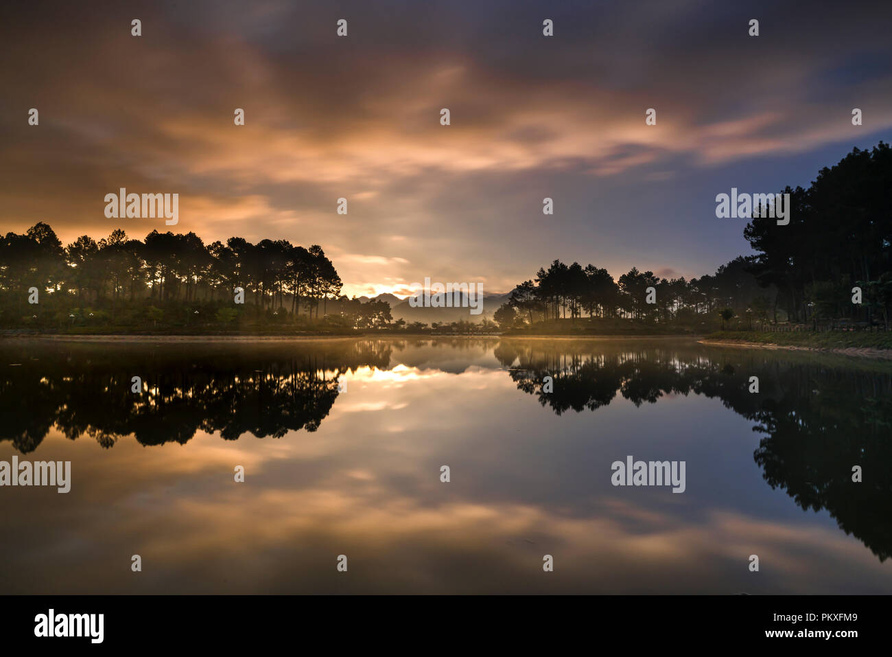 Beautiful dawn on the lake with pink clouds and reflecting sun rays at ...