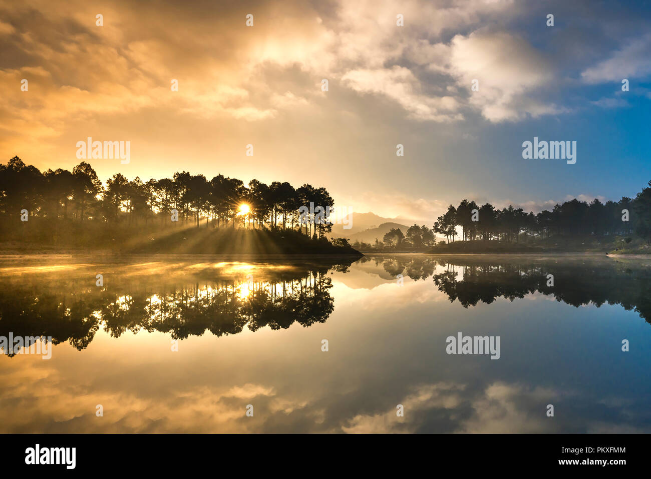 Beautiful dawn on the lake with pink clouds and reflecting sun rays at ...