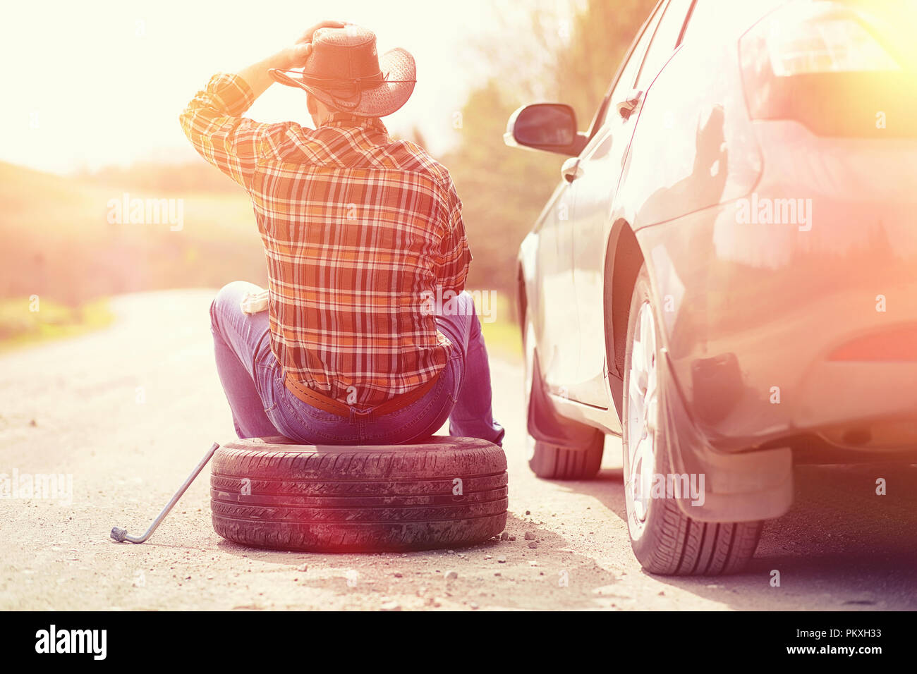 Man is sitting on the road by the car Stock Photo - Alamy