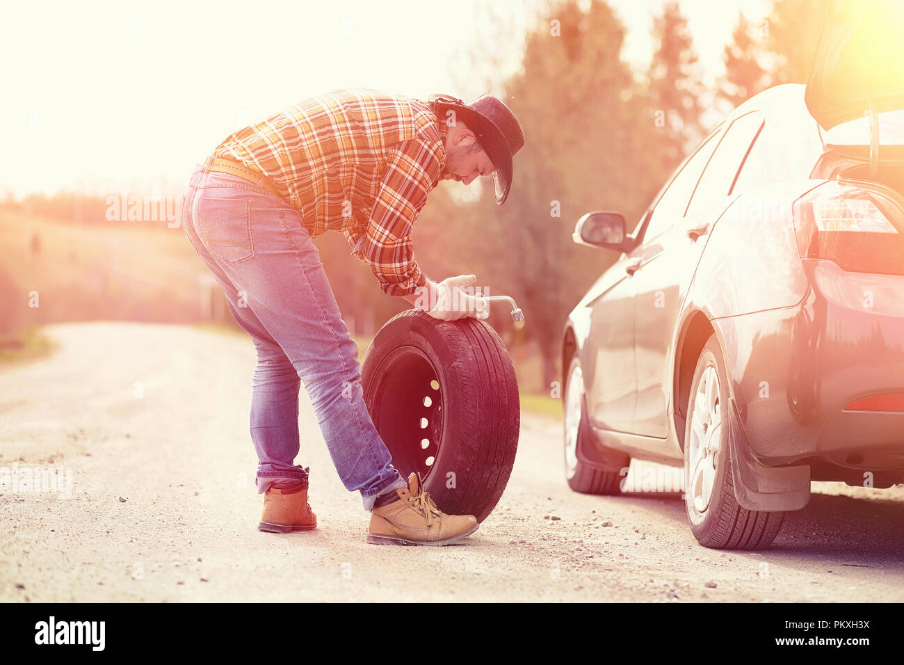 Man is sitting on the road by the car Stock Photo - Alamy